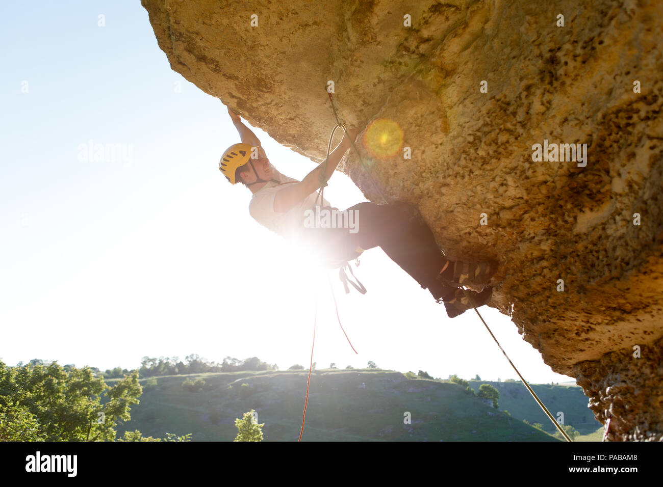 Photo of male climber in helmet clambering up cliff Stock Photo - Alamy