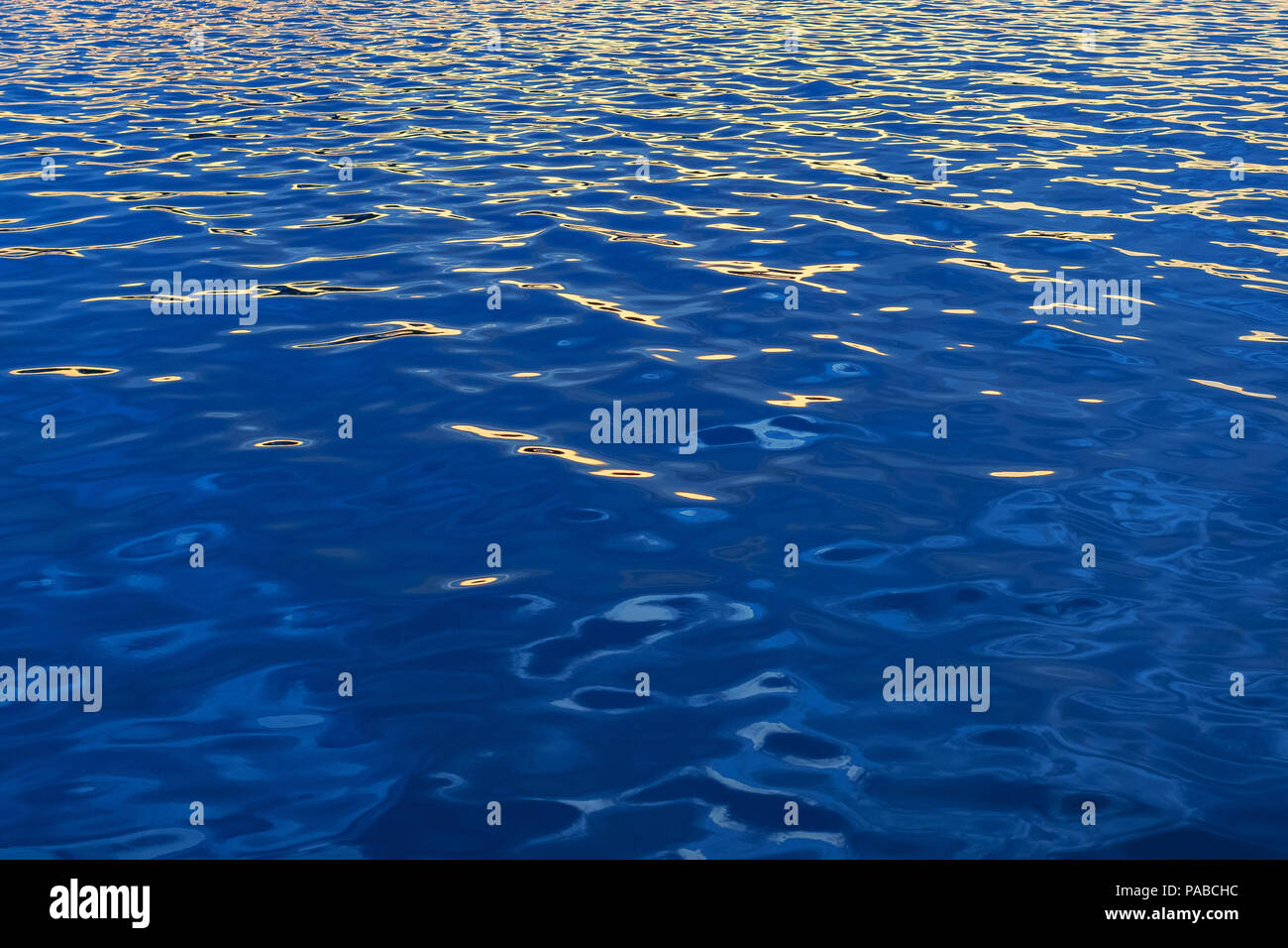 Calm water at sea with some small ripples and waves in clear blue ...