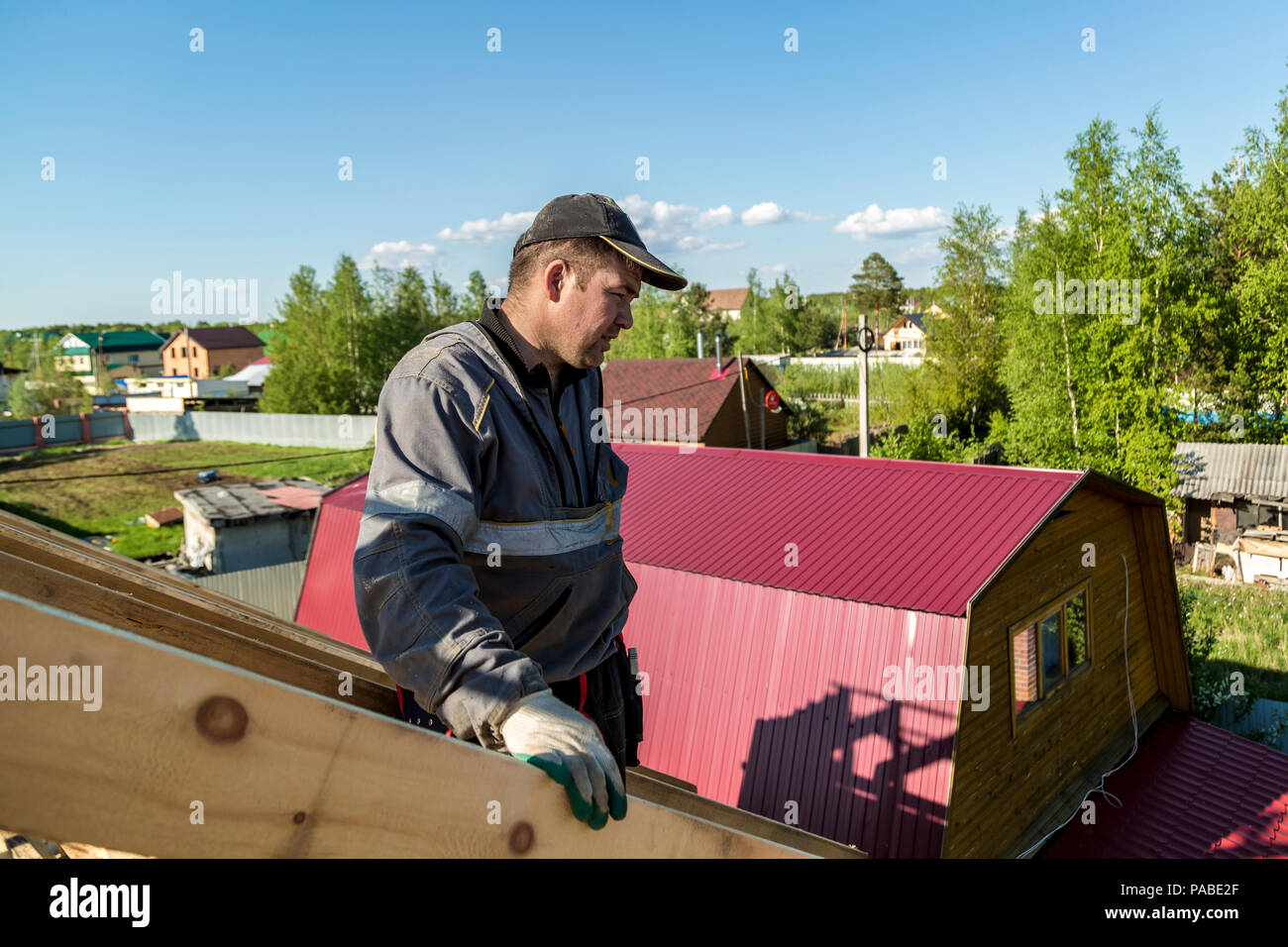 The builder stands on the roof of a wooden house and thinks how to put ...