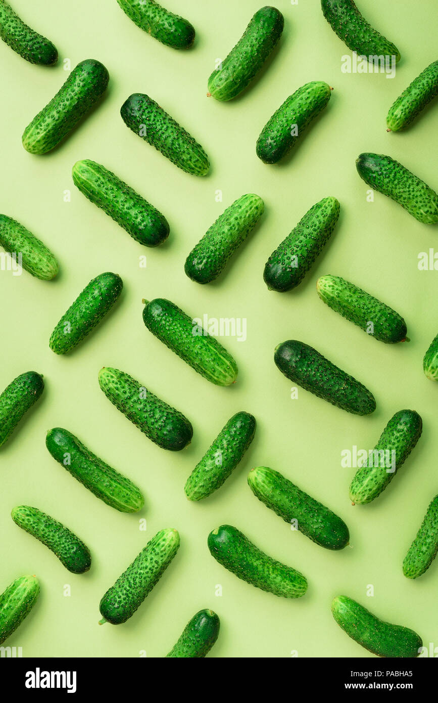 Creative pattern of fresh cucumbers on green background. Top view. Copy ...