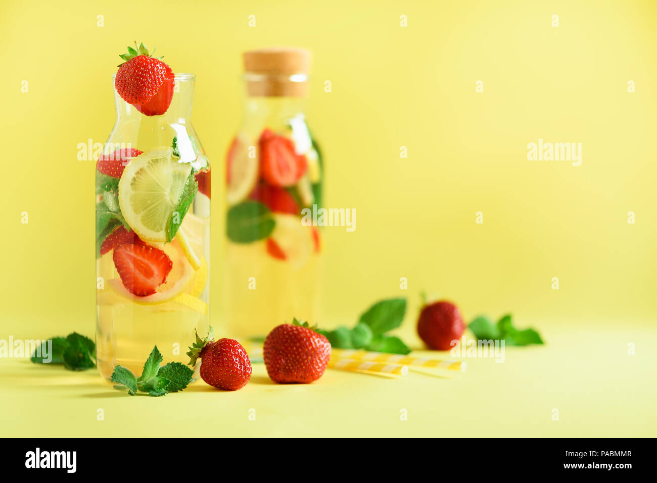 Fresh fruit flavored water with strawberry, lemon, mint on yellow ...