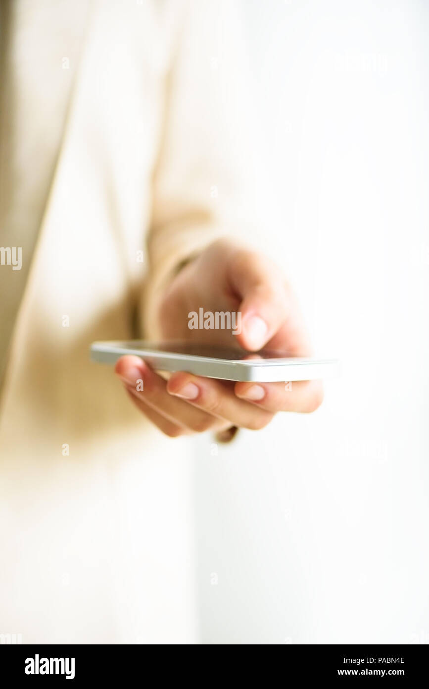 Woman hands hold cell phone on light cream background with copy space ...