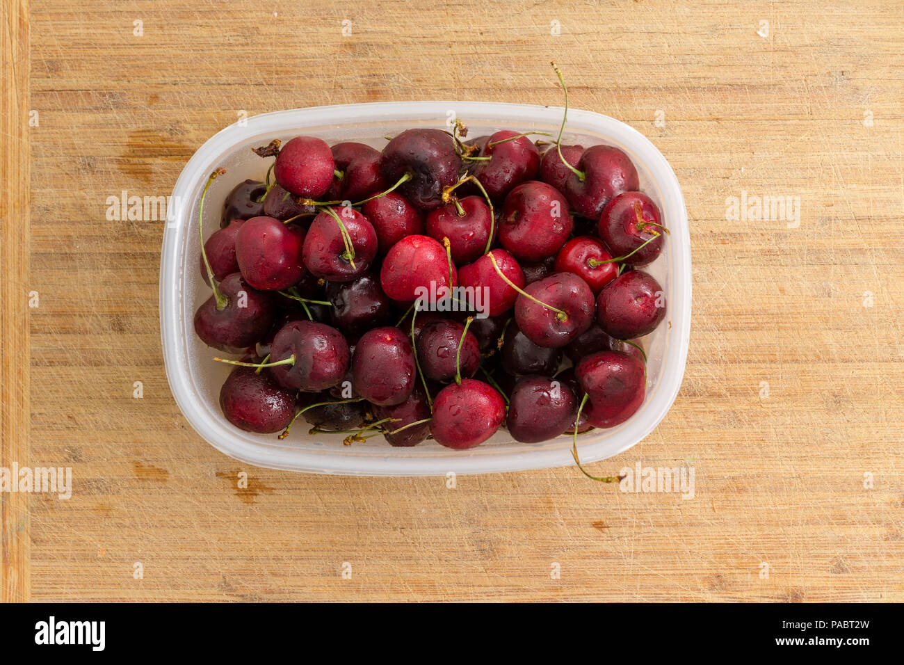 Punnet filled with fresh whole ripe red summer cherries placed in the ...
