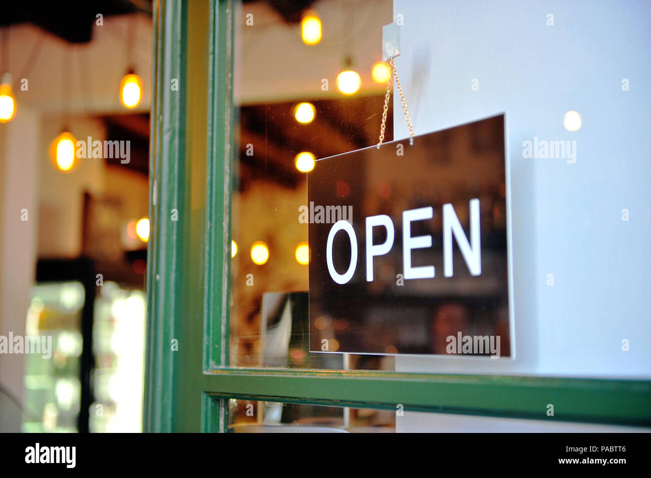 Black hanging open sign in the green wooden door of retail store ...