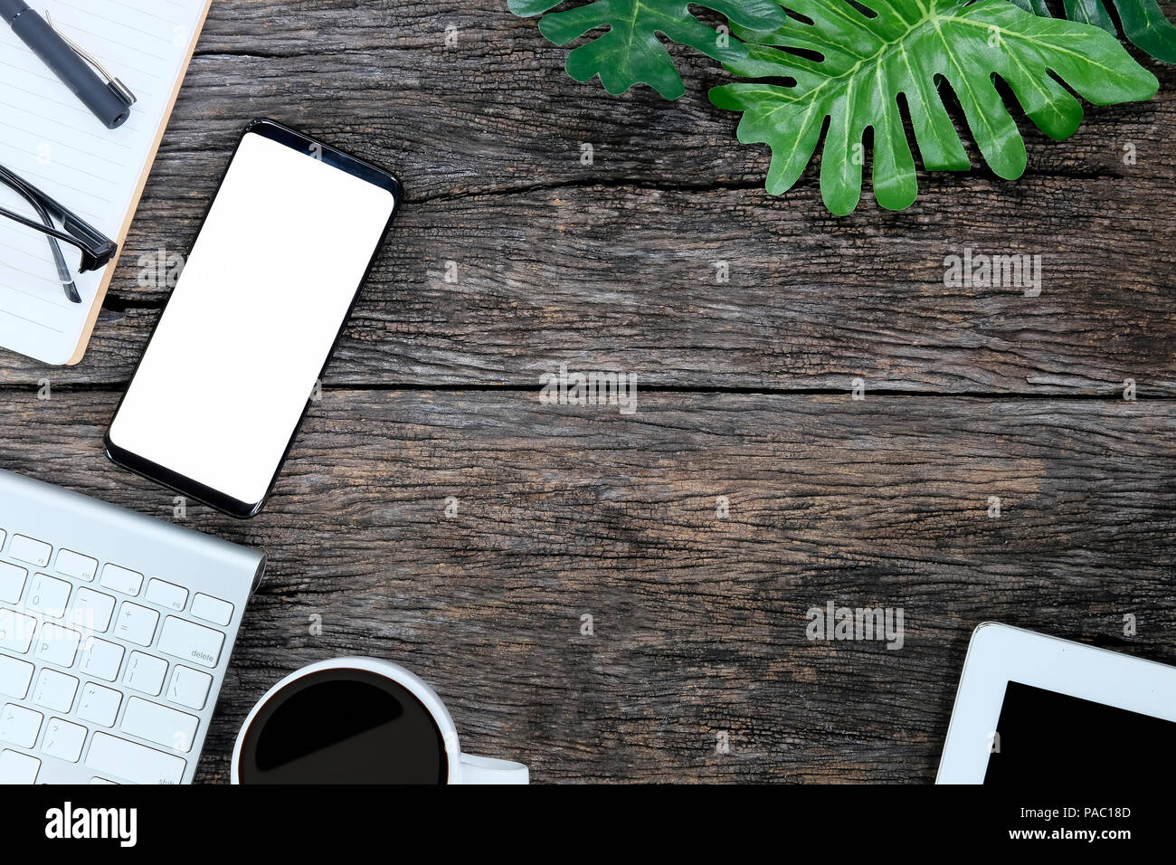 Smartphone white screen on wooden table and supplies with keyboard and ...