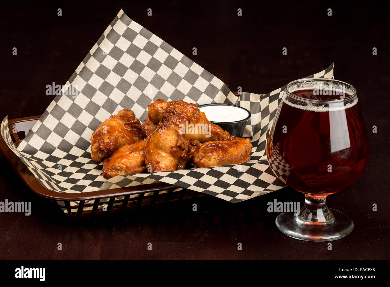 Glazed wing basket in a restaurant with a beer in a fancy glass Stock ...