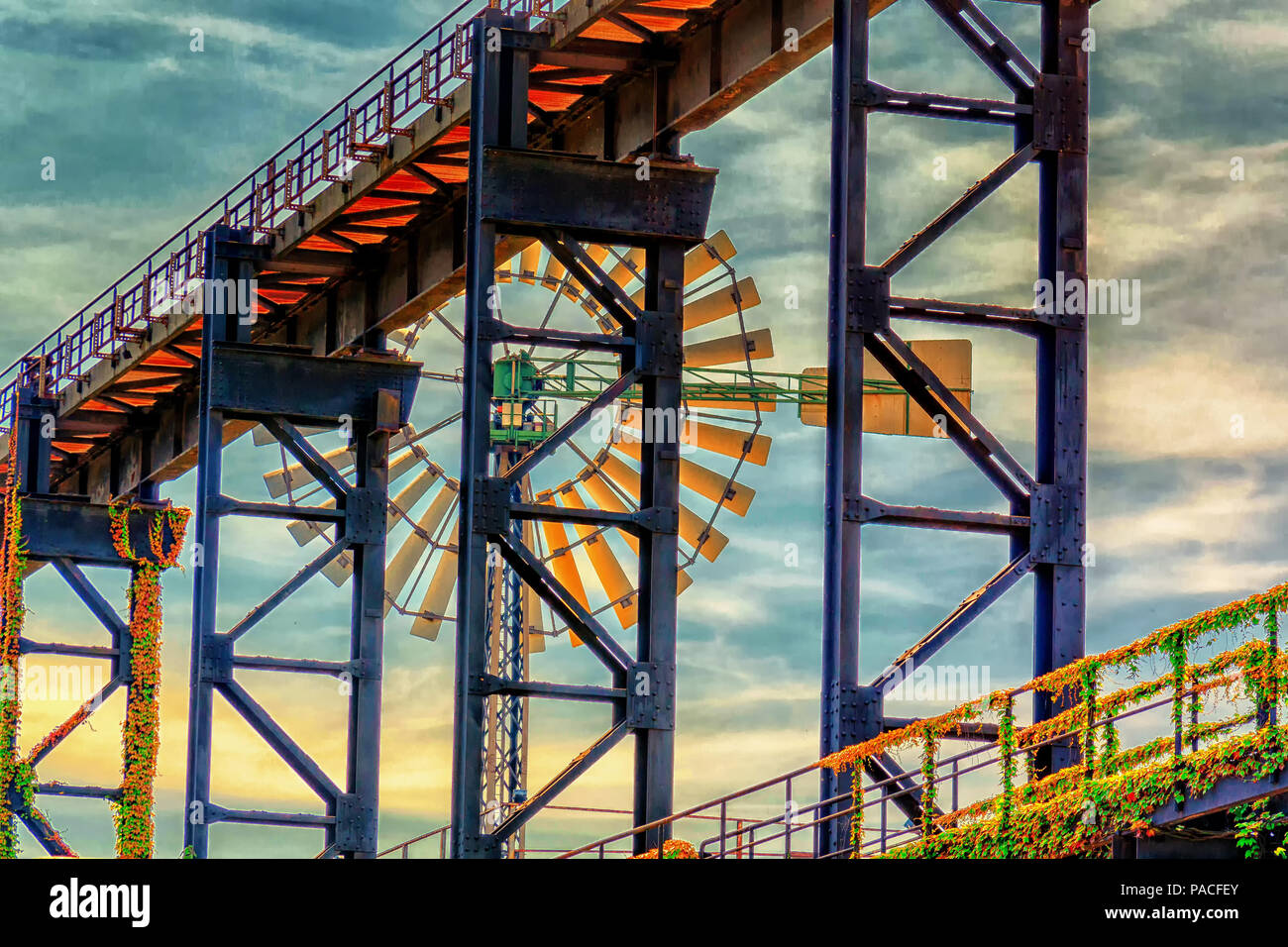 Metal pedestrian bridge riveted in front of a dramatic sky. In the ...