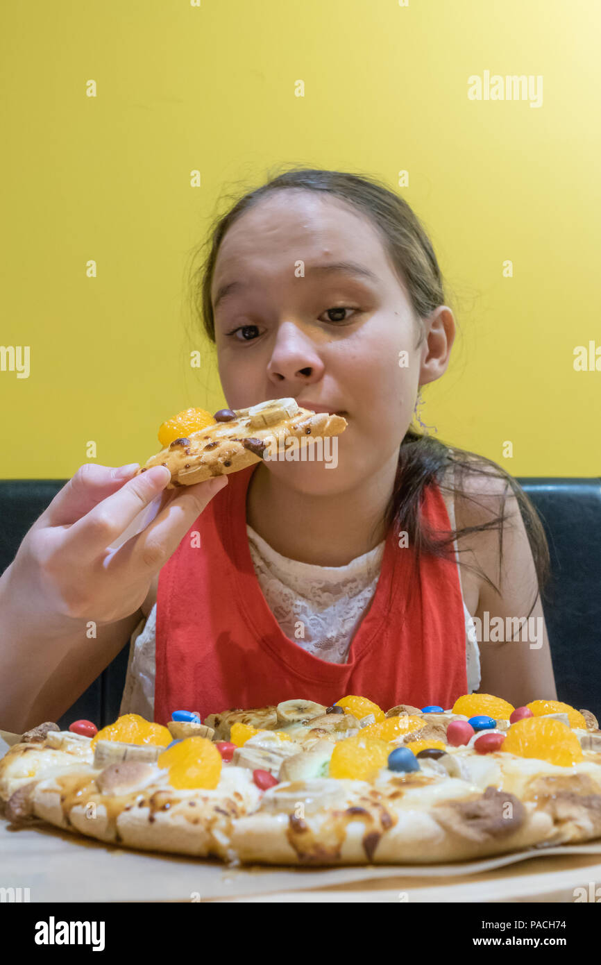 Young mixed race tween girl eating candy, marshmallow, and chocolate ...