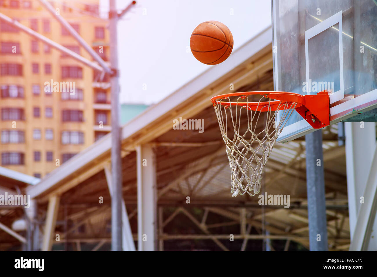 Action shot of basketball falls through basketball hoop and net on park ...
