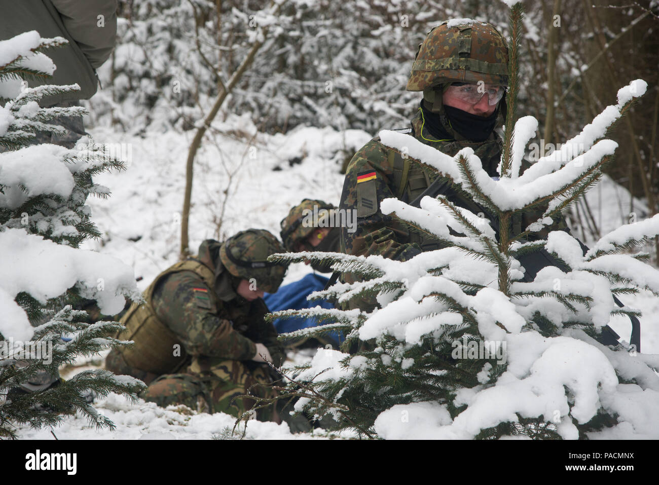 A German medical soldier, on right provides security as other soldiers ...