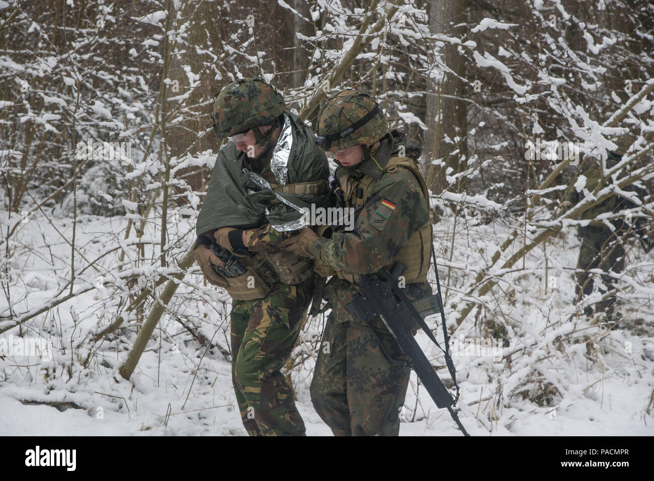A German medical soldier, right, assists a role player with wounds from ...