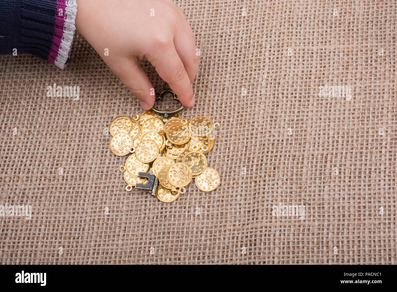 Hand holding a retro styled key over fake gold coins Stock Photo - Alamy