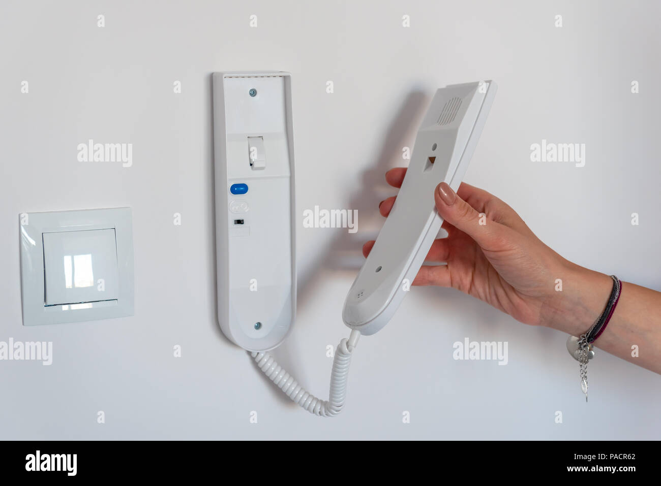 A woman's hand holding the intercom to open the door Stock Photo - Alamy