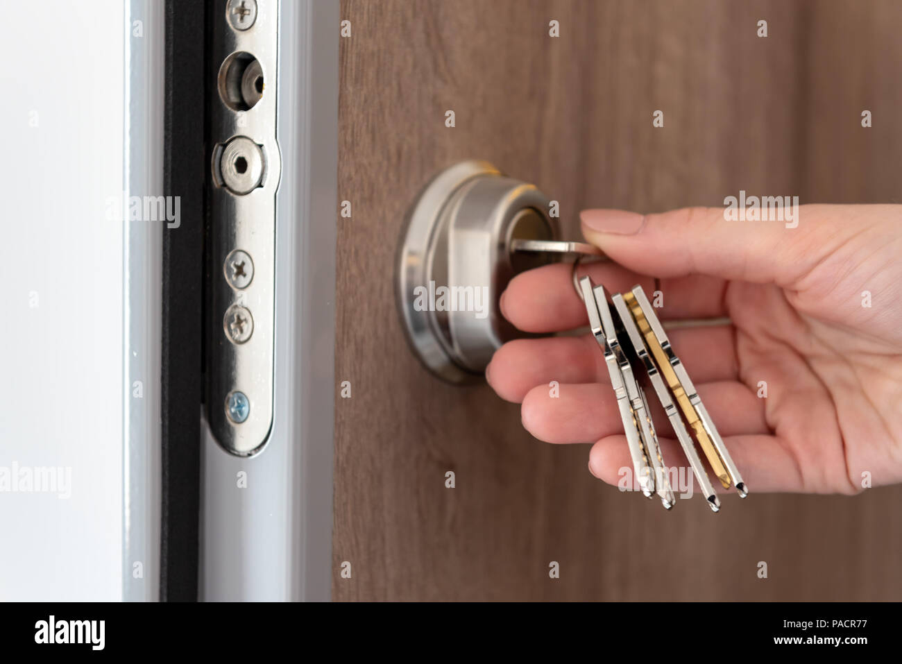 Female hand locking entrance door with a key Stock Photo - Alamy