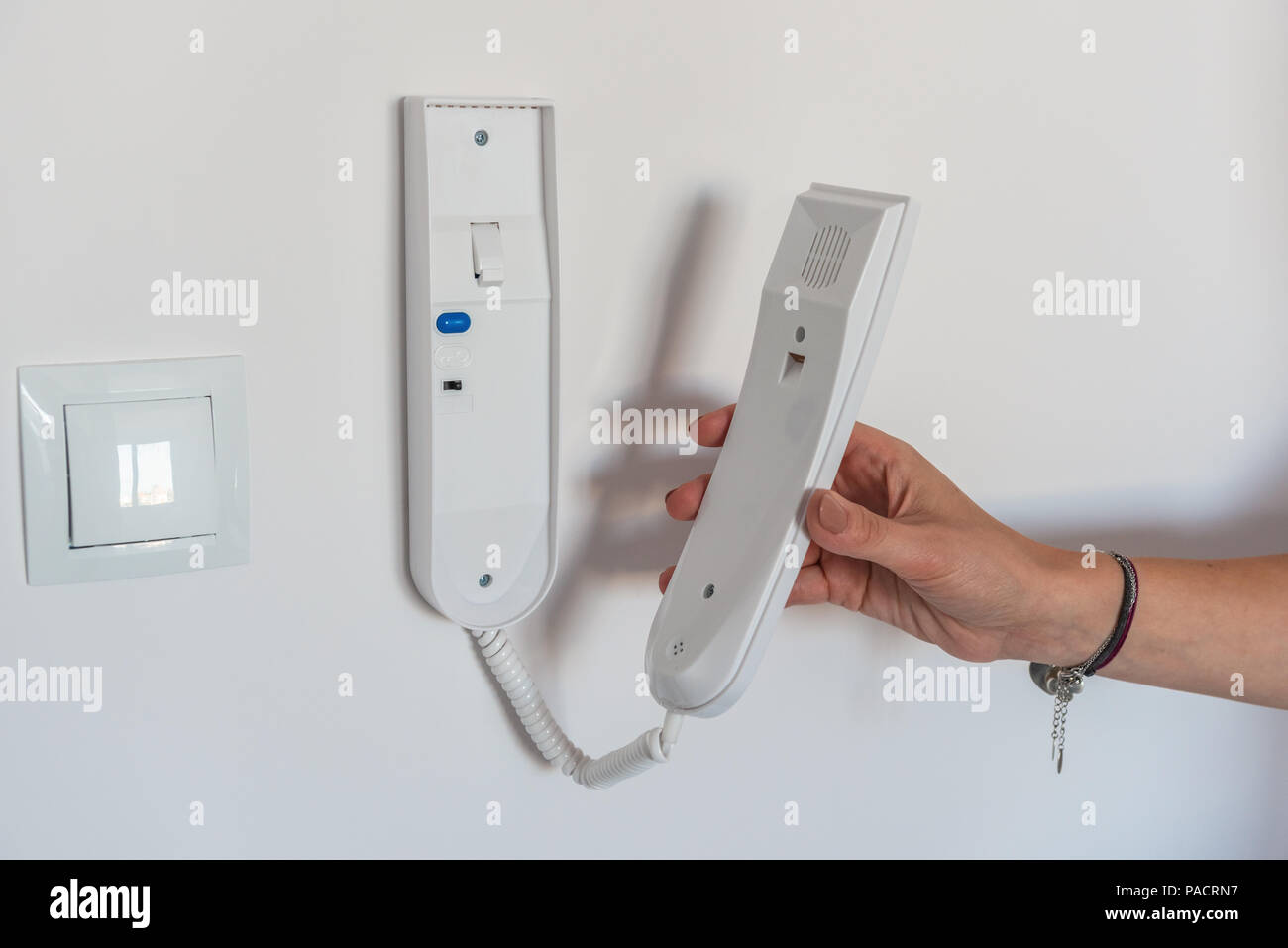 A woman's hand holding the intercom to open the door Stock Photo - Alamy