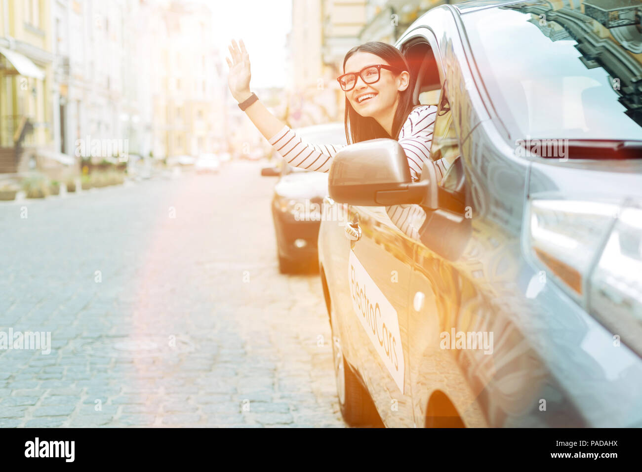 Positive woman waving to the passersby Stock Photo - Alamy
