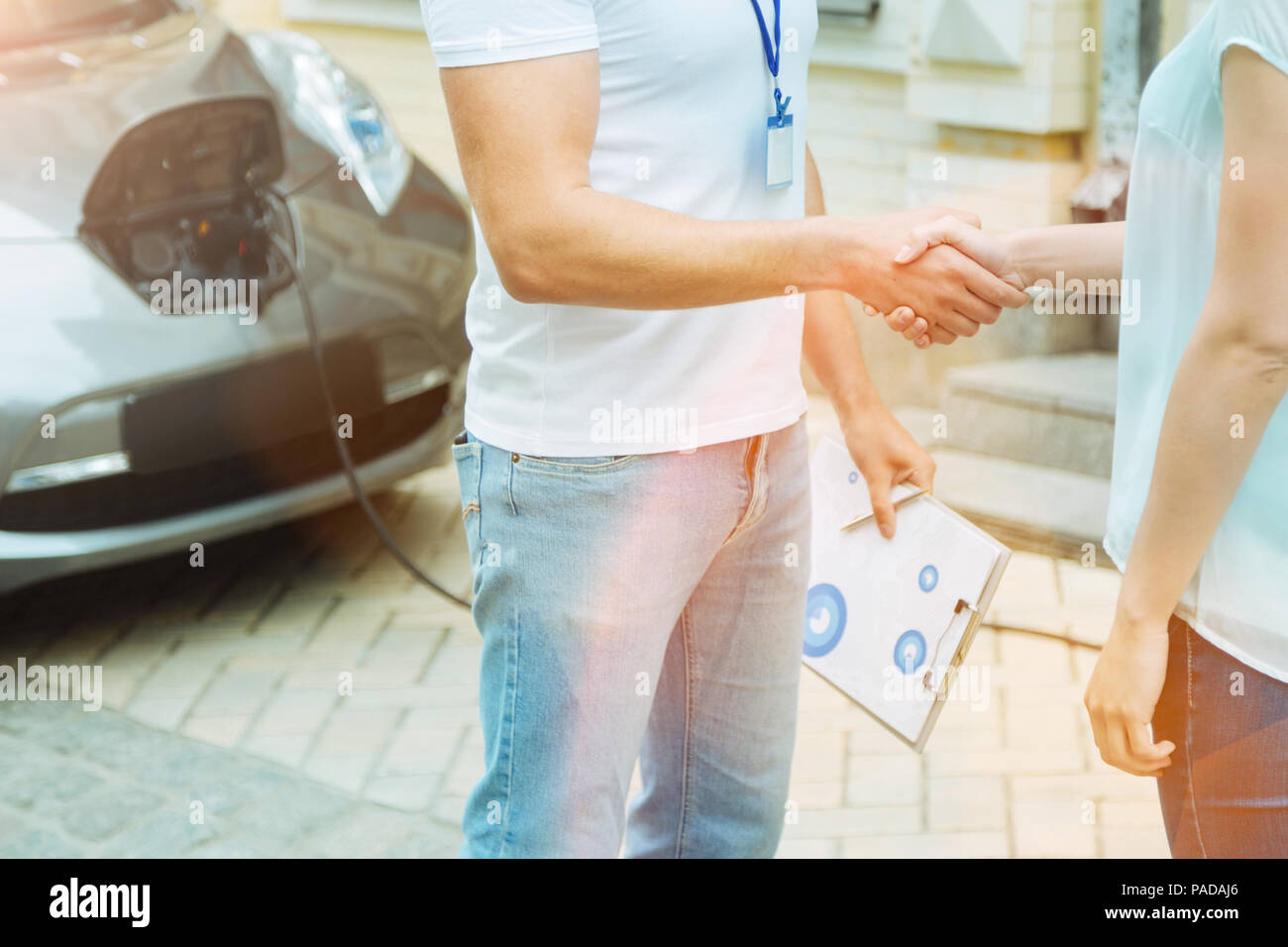 Two people shaking hands while standing near the car Stock Photo - Alamy
