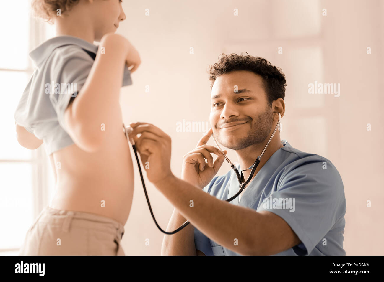 Positive delighted medical worker treating boy Stock Photo - Alamy