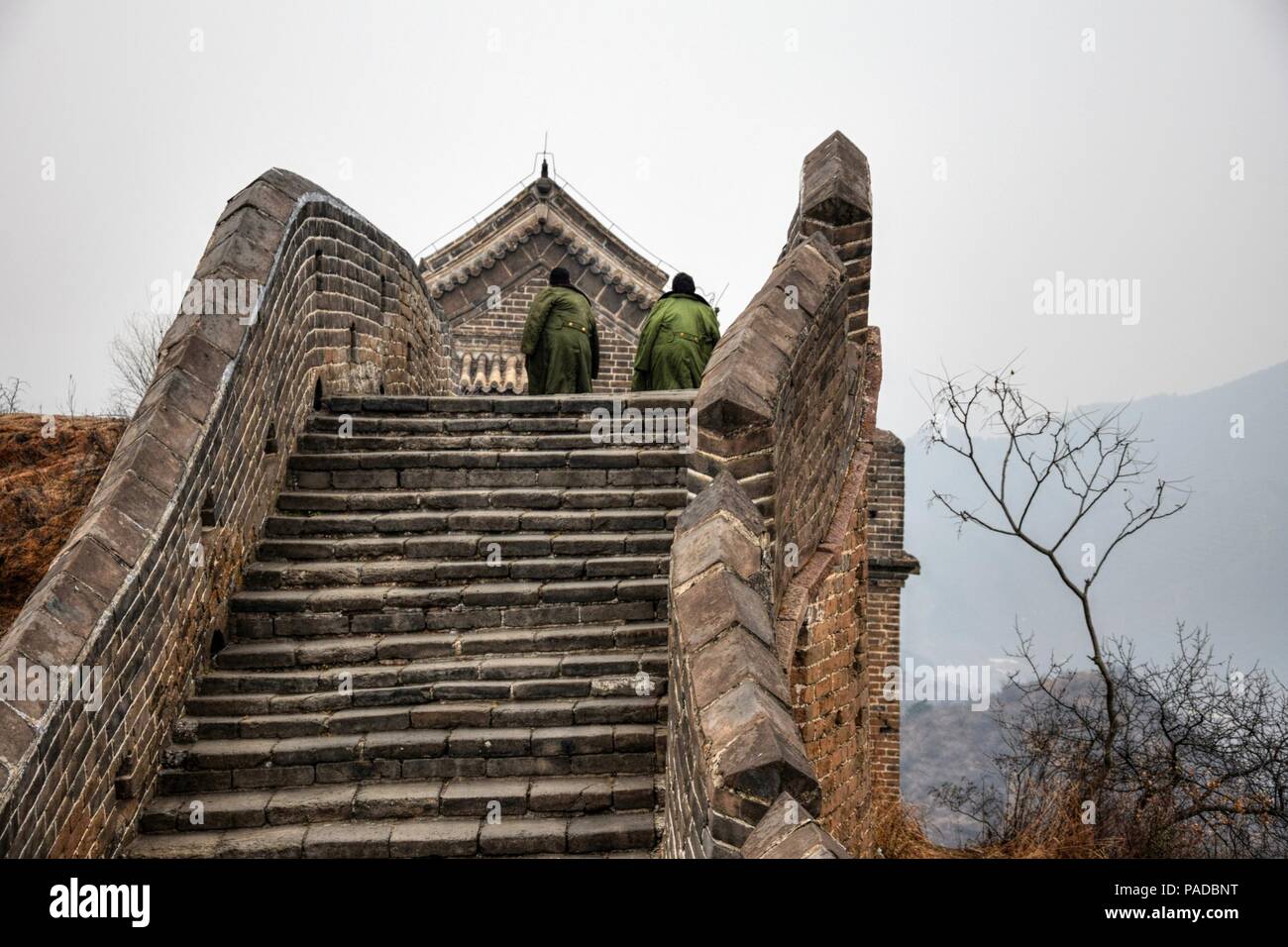 Two men dressed in the winter green army coat climb the stairs on the ...