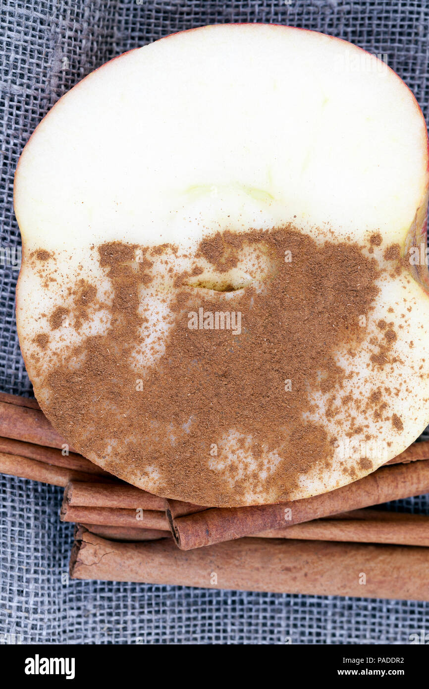 whole cinnamon sticks and chopped cinnamon on half of apple, closeup ...