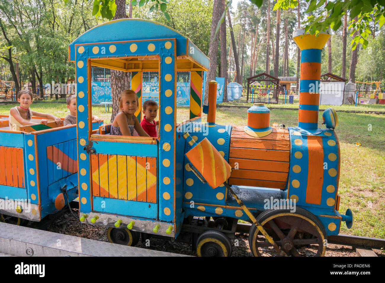 Four little children are riding on a children's train in the park Stock ...