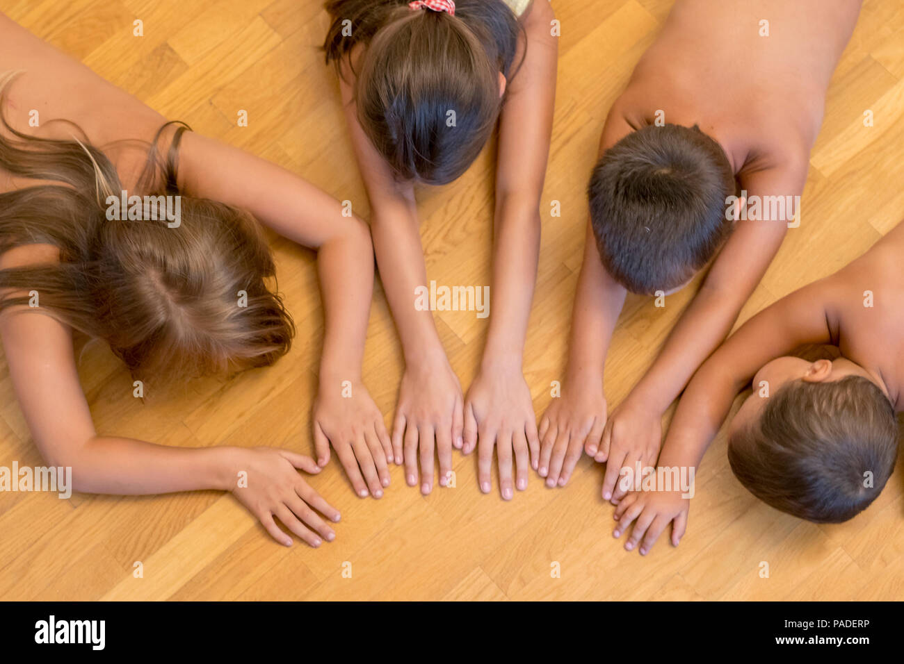 Four children lie on the parquet floor. Four kids are on the floor ...