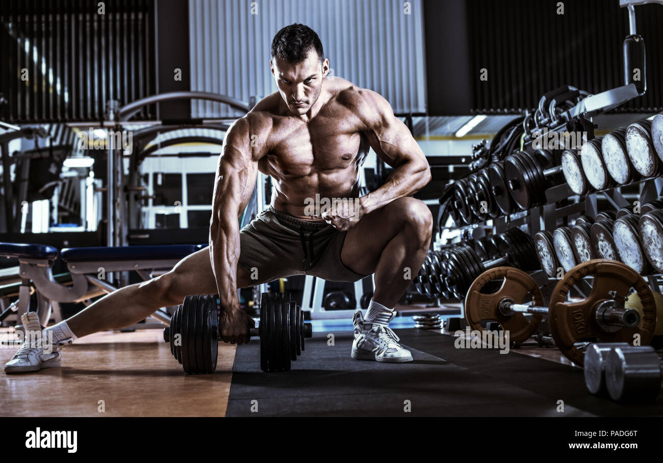 bodybuilder man, execute exercise with dumbbells, inside gym ...
