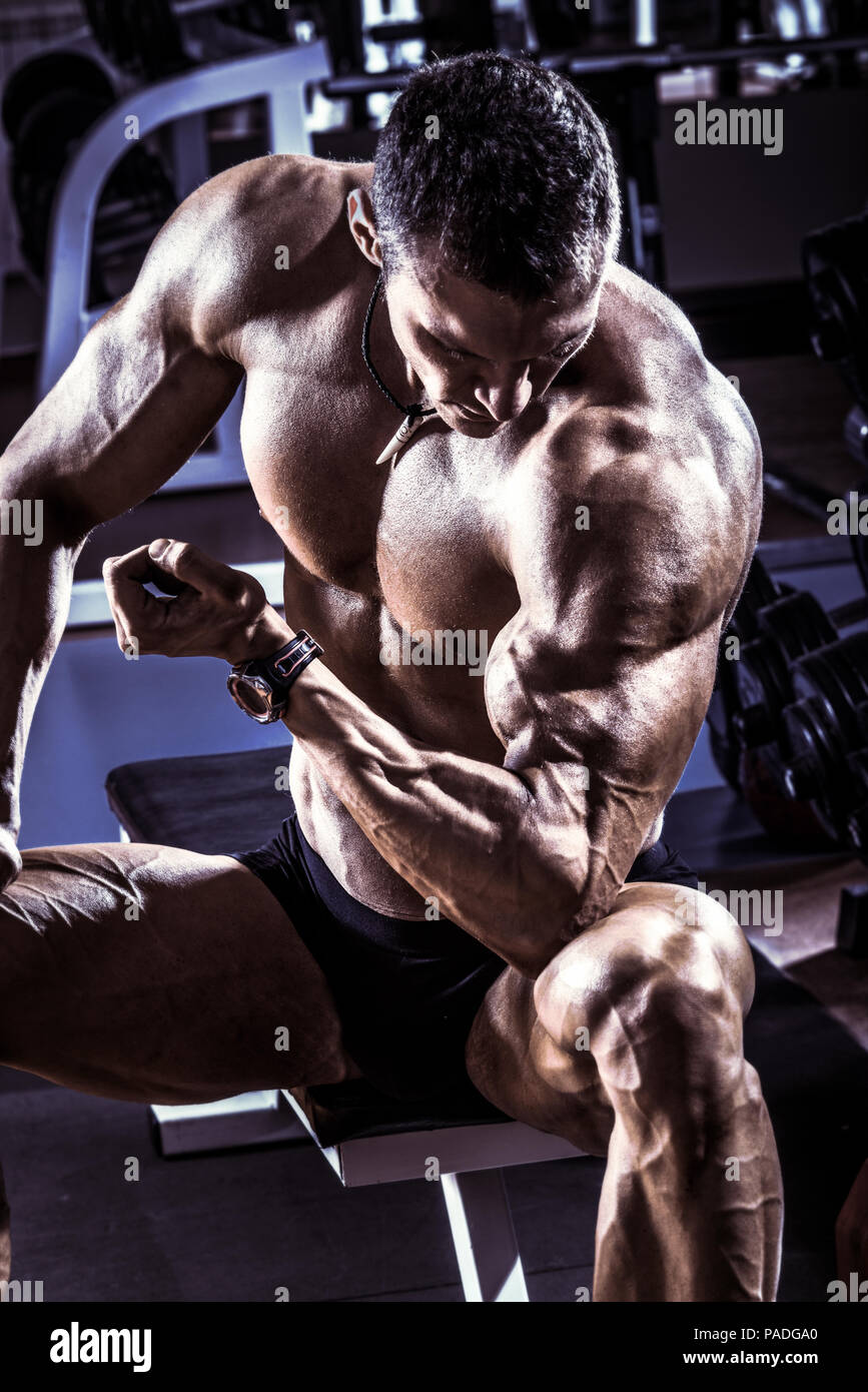 very power athletic guy , execute exercise with dumbbells, on gym ...
