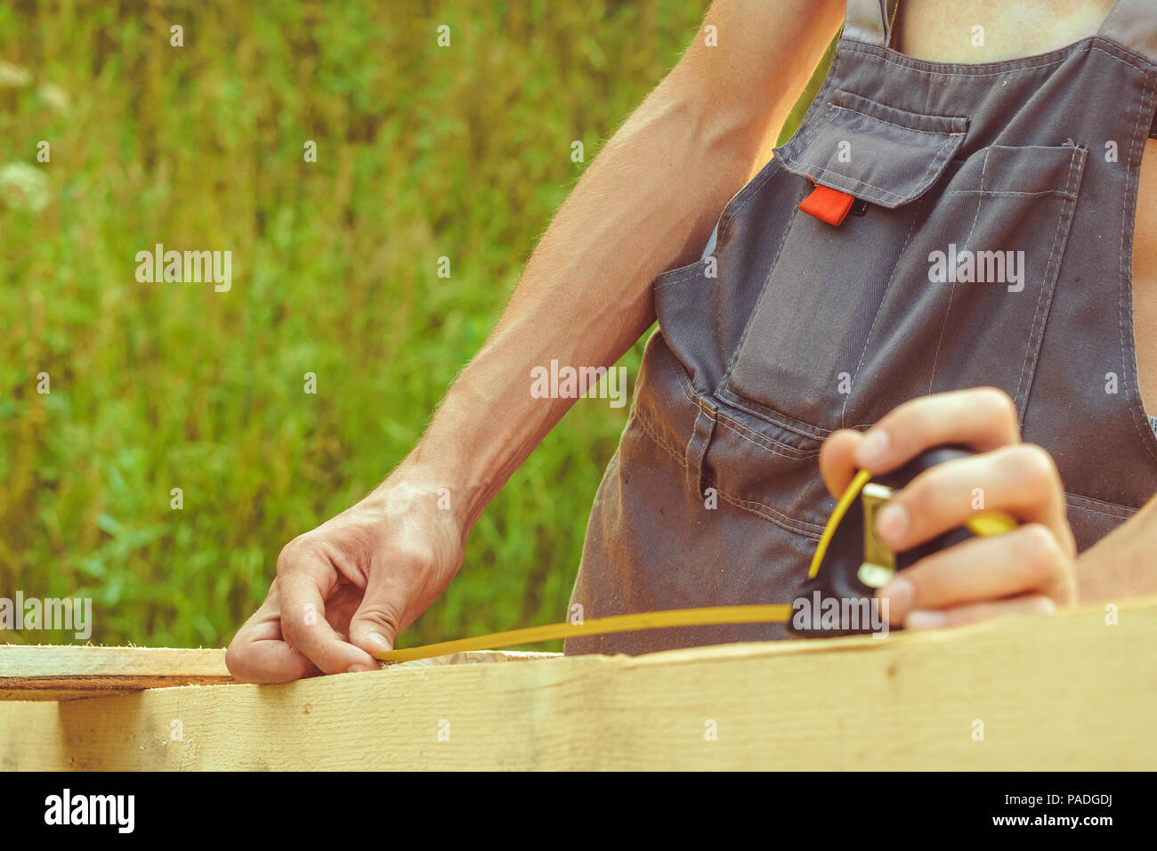 The worker makes measurements of a board with the help of a ruler, a ...
