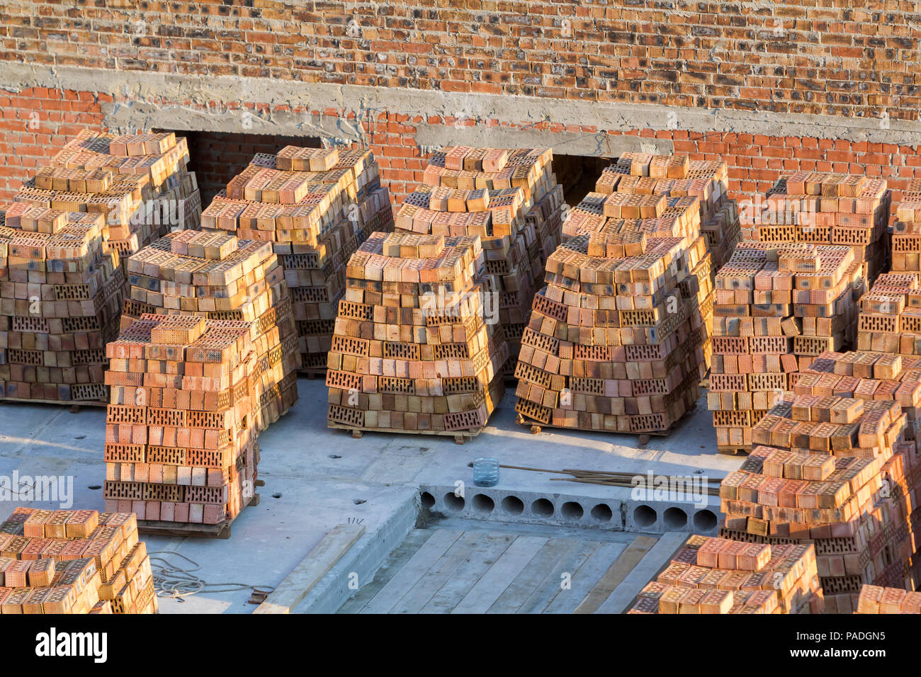 Close-up stacks of red brick neatly piled on concrete foundation of ...