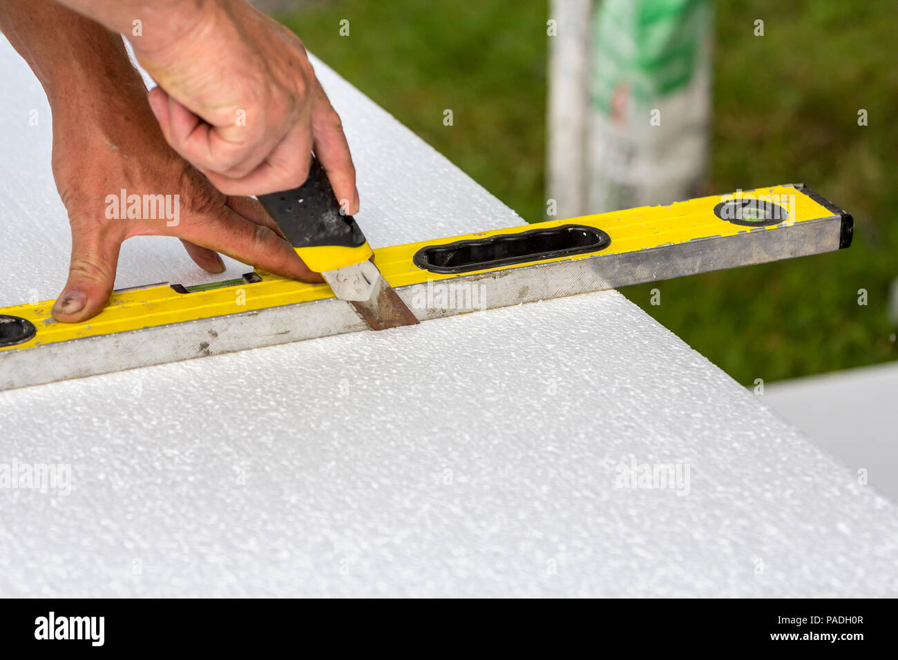 Close-up of worker hand with knife and level cutting white rigid ...