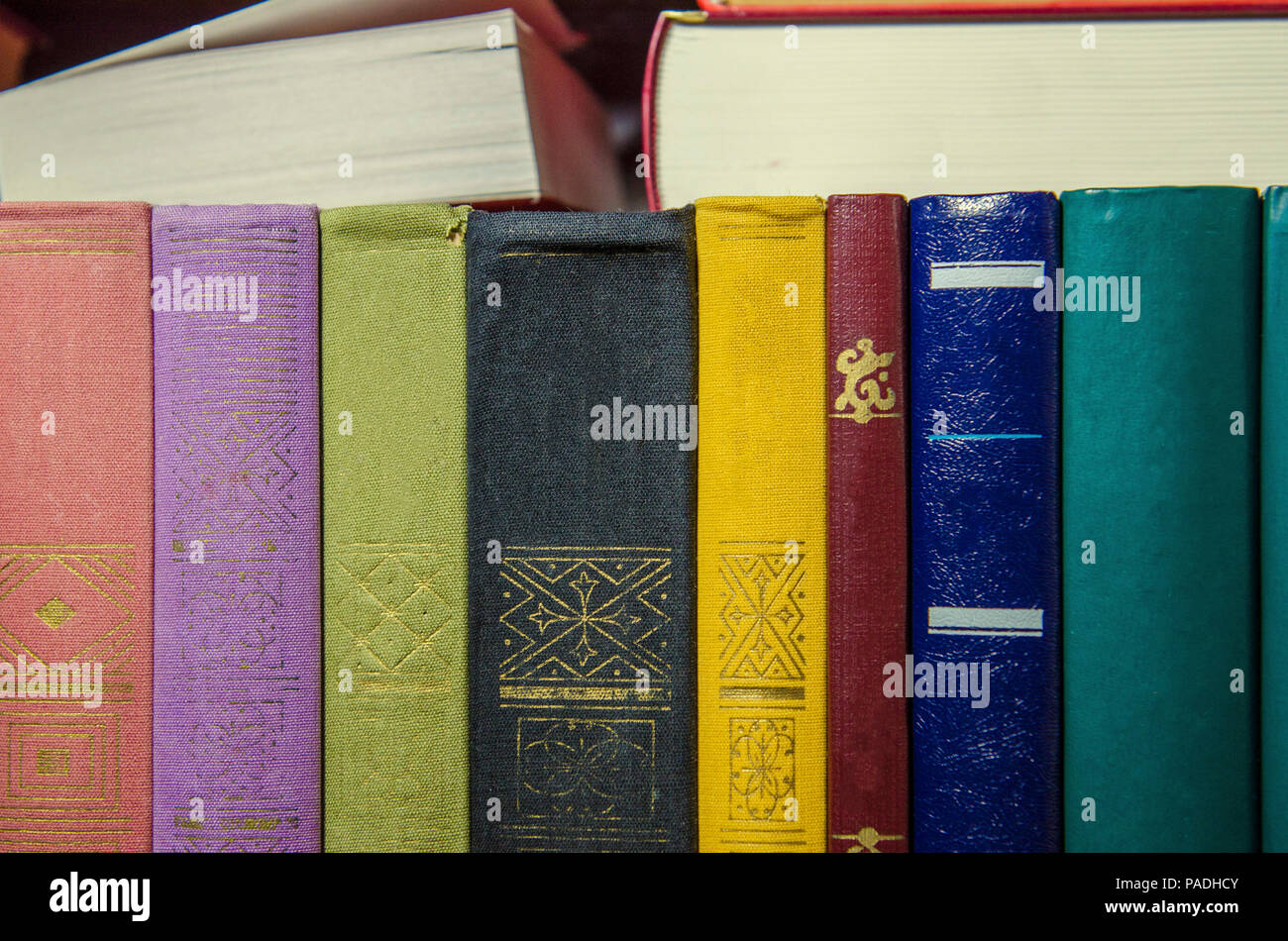 a stack of colorful books on the shelf in a library or a room close-up ...