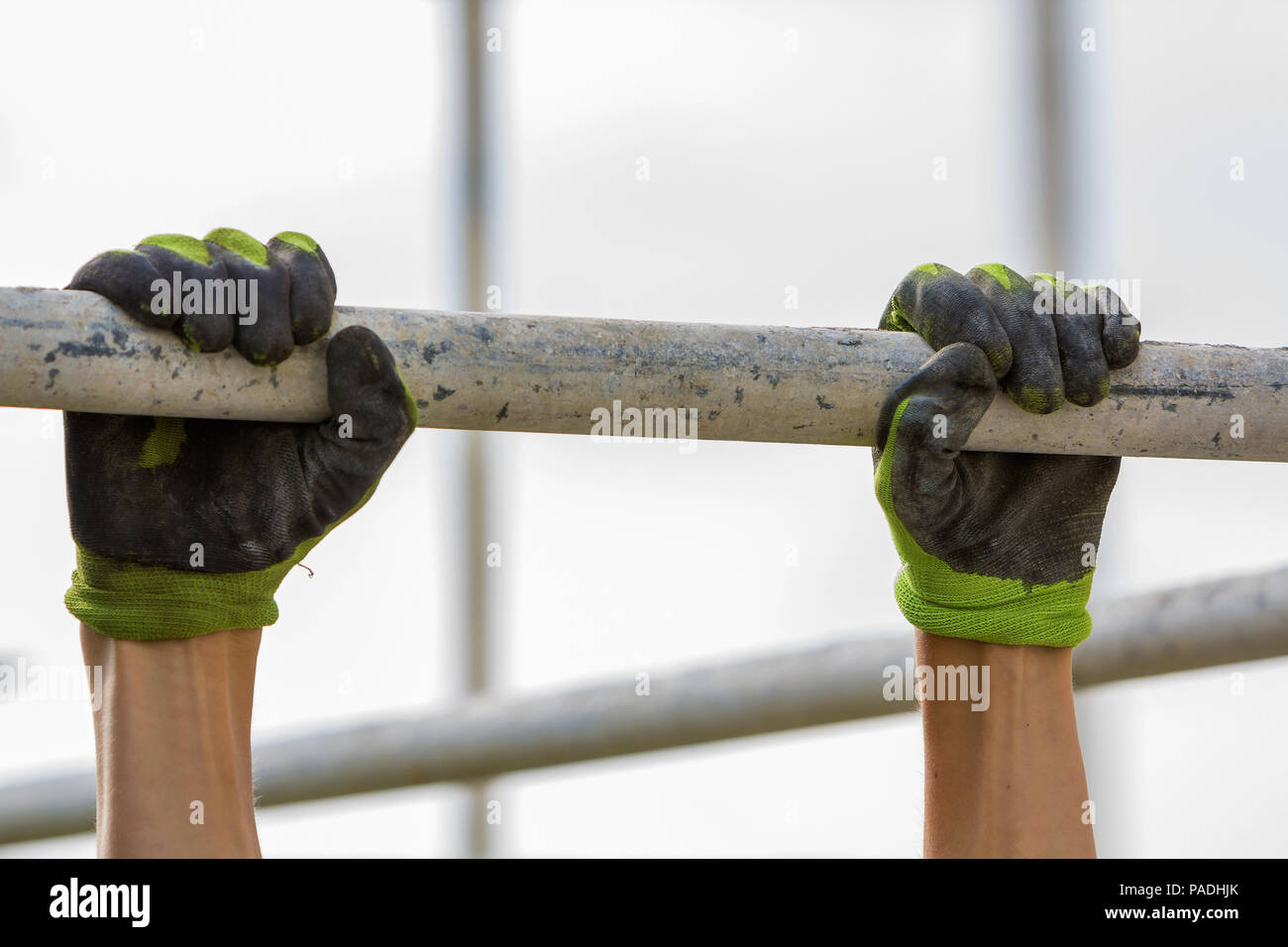 Close-up of muscular worker hands hanging on scaffold metal pipe on ...