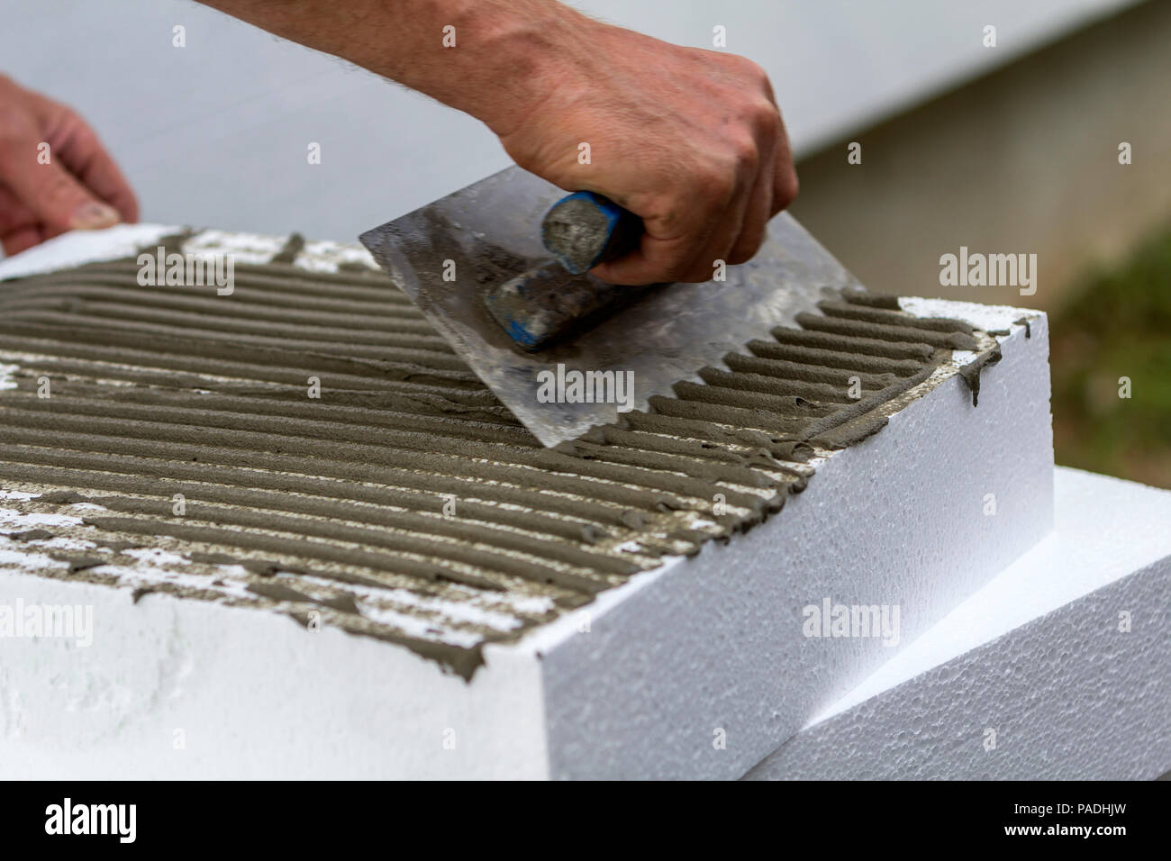 Close-up of worker hand with trowel applying glue on white rigid ...