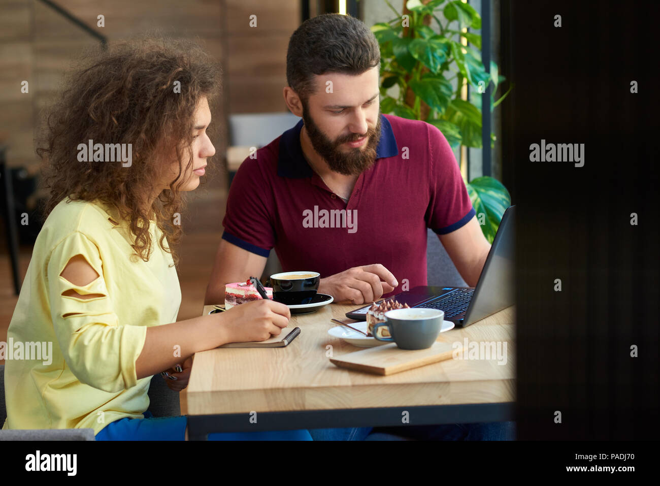 Young students working using laptop, working, studying in restaurant ...