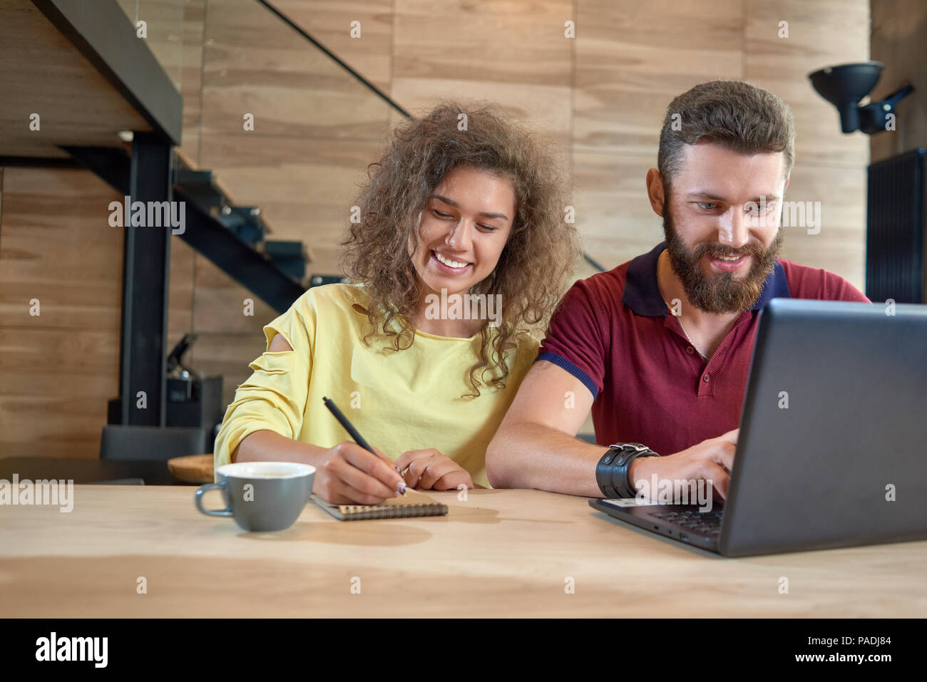 Studying students sitting in comfortable cafe, using laptop,smiling ...