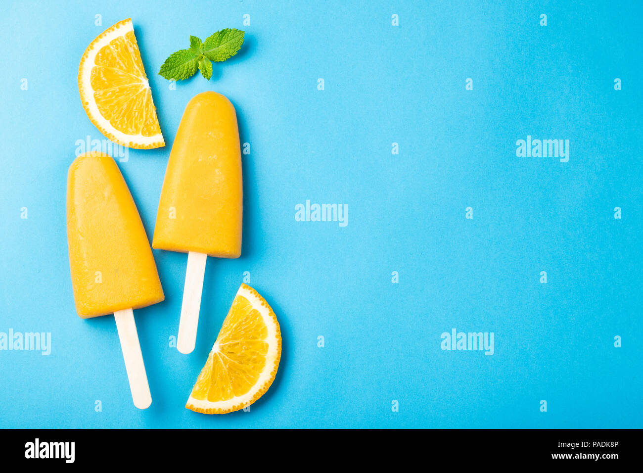 Orange popsicles with juice on a blue bacground. Ice pops, flat lay ...