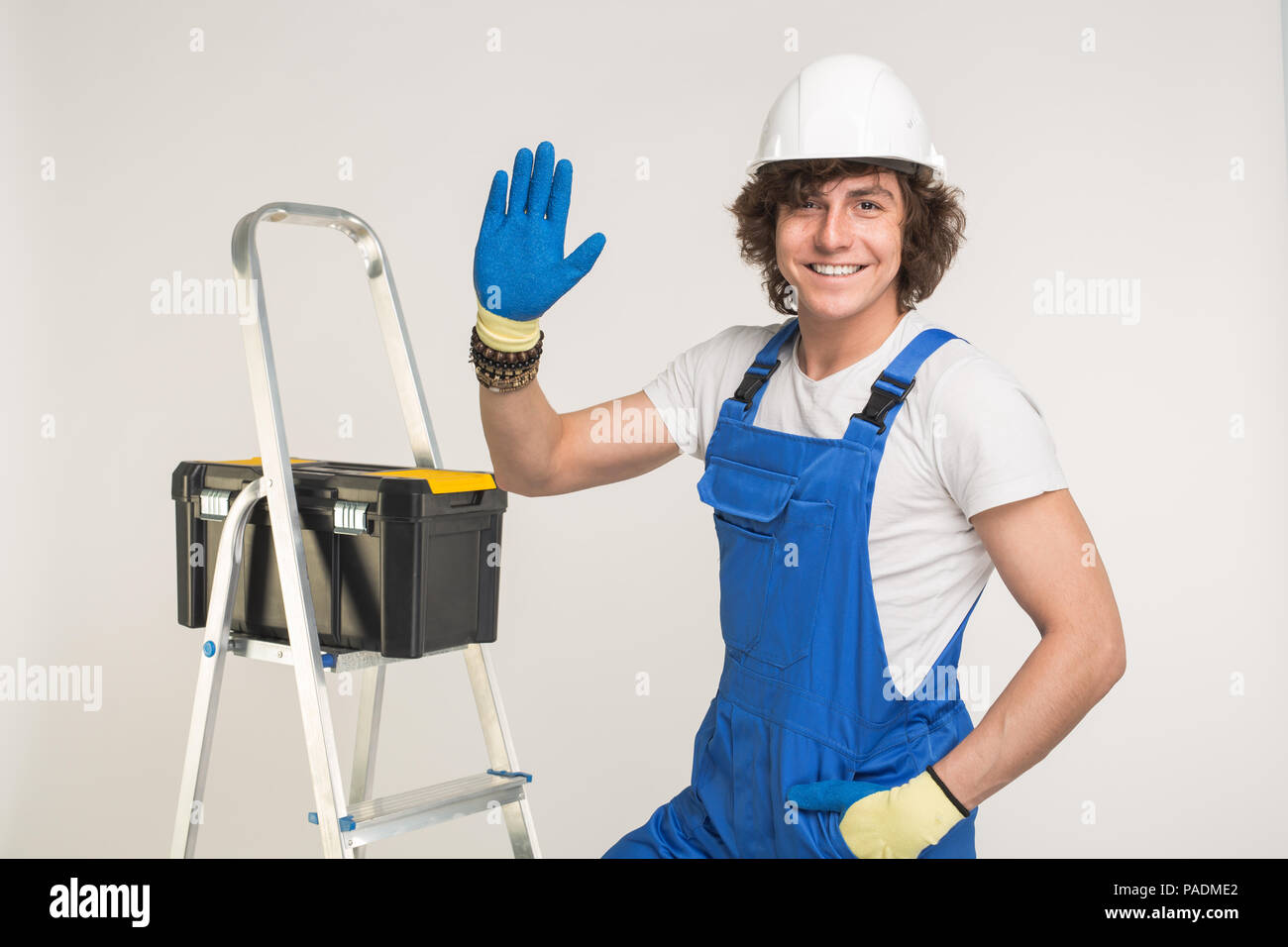 Studio portrait of handsome builder in white helmet and blue overall ...