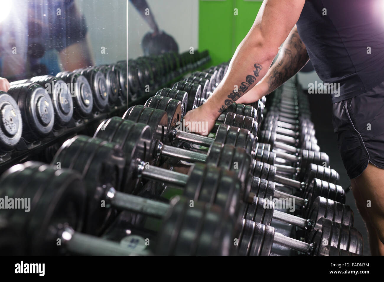 Strong man's hand takes a heavy dumbbell in gym Stock Photo - Alamy