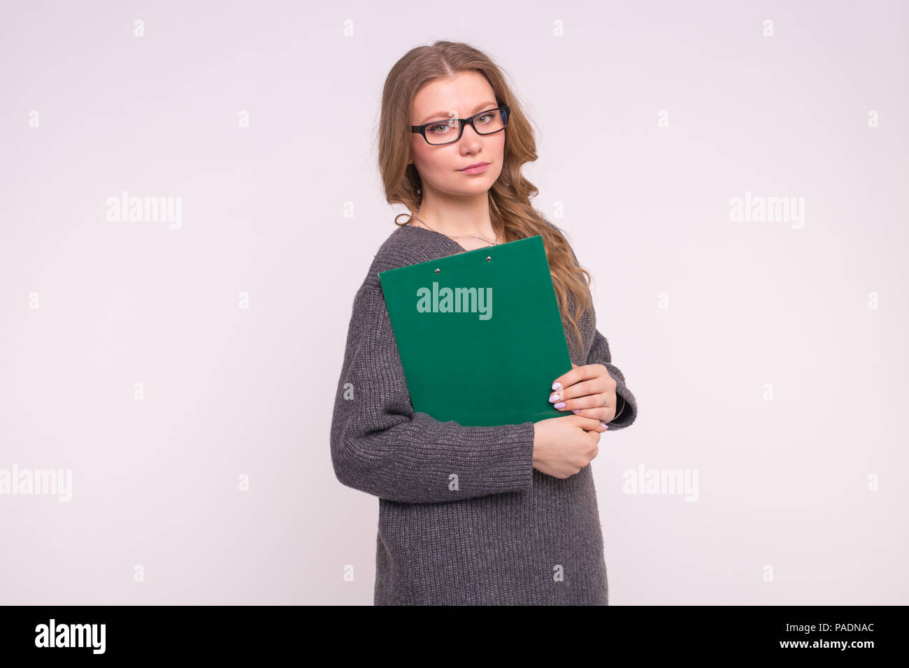 Smart beautiful girl in glasses with paper folder, wearing grey ...
