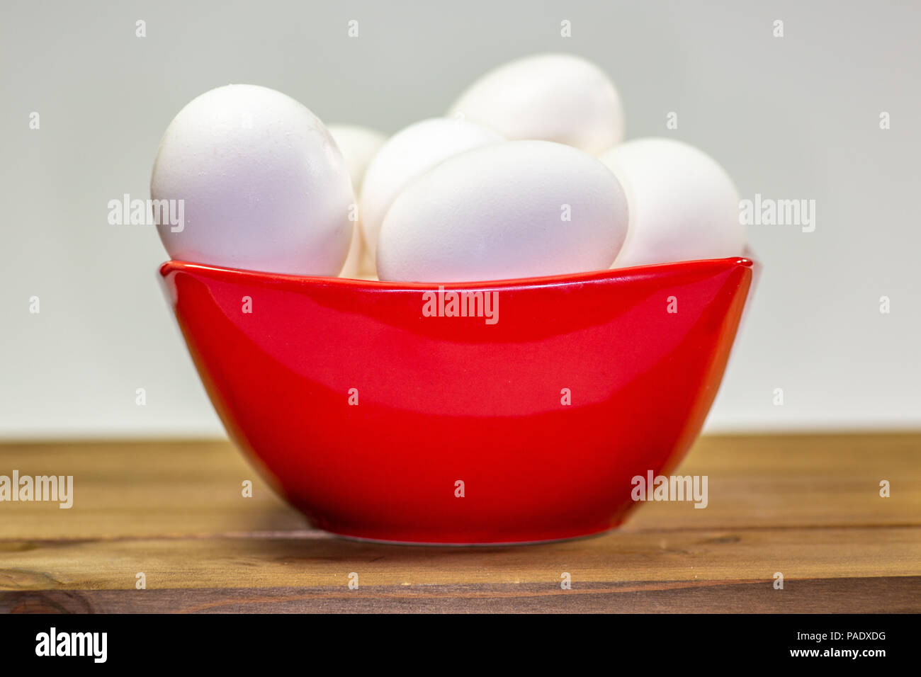 A group of eggs inside a deep red bowl waiting for the chef to use them ...