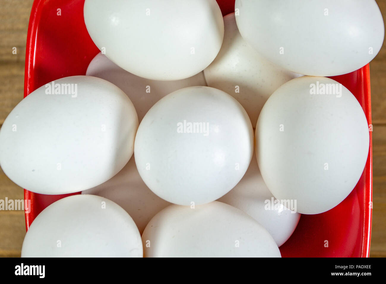 A group of eggs inside a deep red bowl waiting for the chef to use them ...