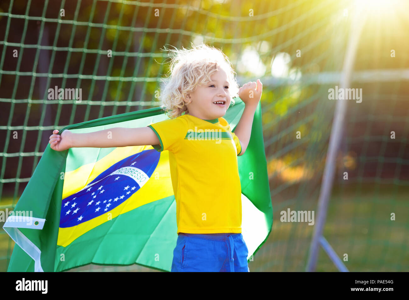 Kids play football on outdoor field. Brazil team fans with national ...