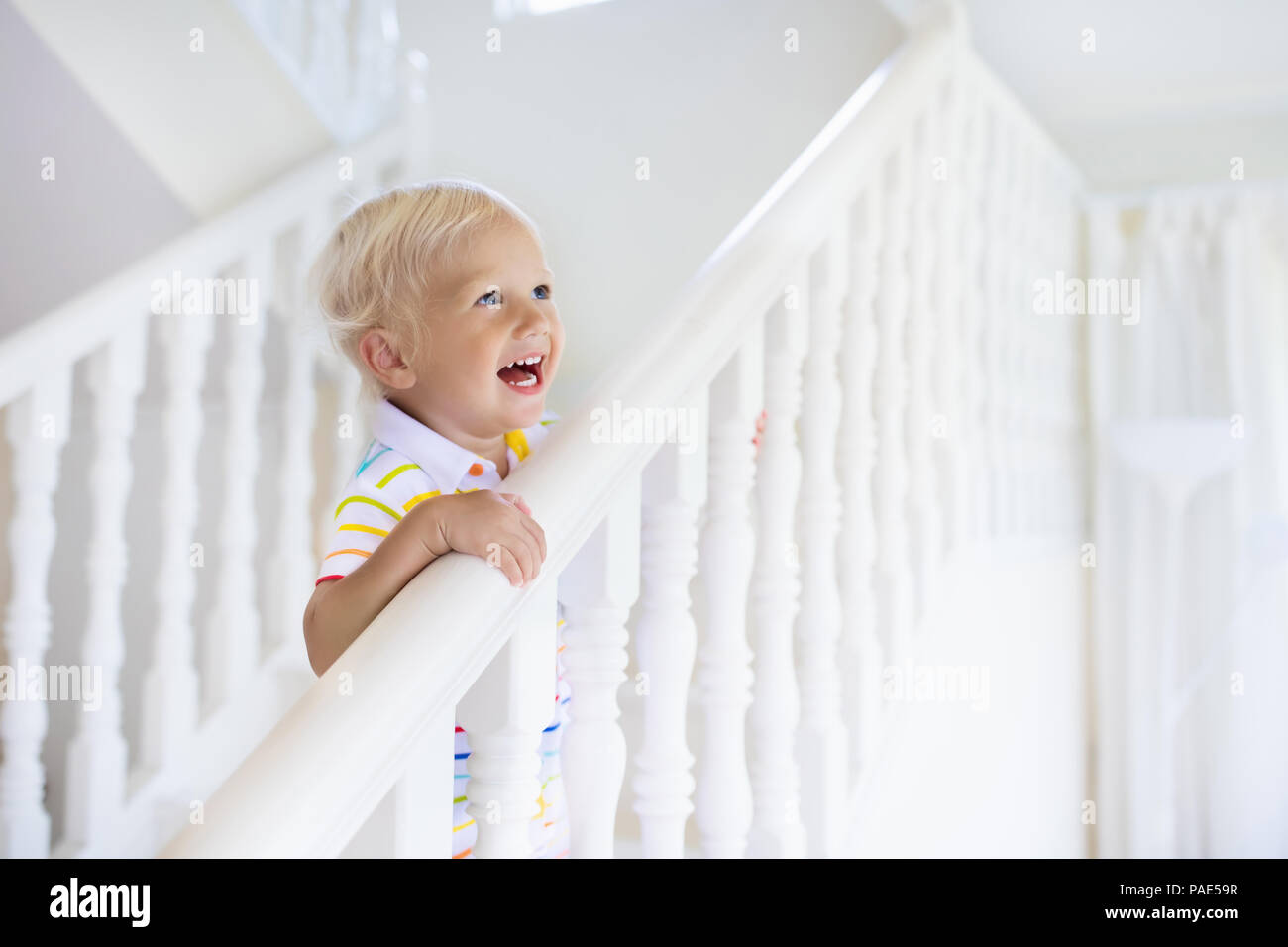 Kid walking stairs in white house. Baby boy playing in sunny staircase ...