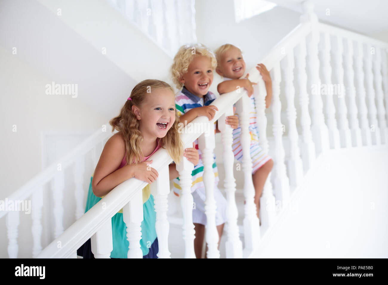 Kids walking stairs in white house. Children playing in sunny staircase ...
