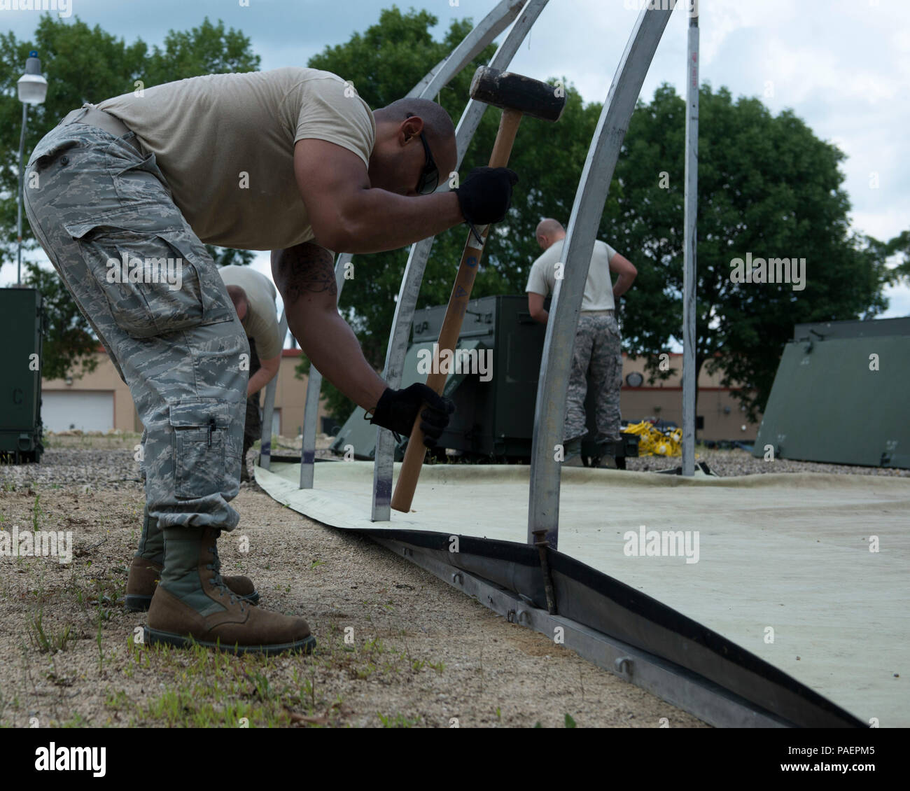 A member of the 103rd Civil Engineer Squadron drives a stake into the ...