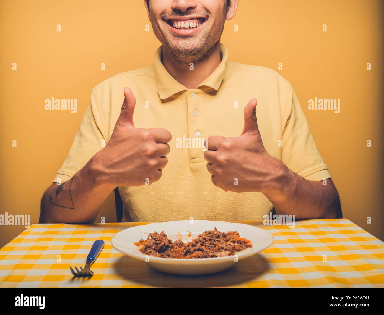 A young man against a yellow backdrop is eating mince Stock Photo - Alamy