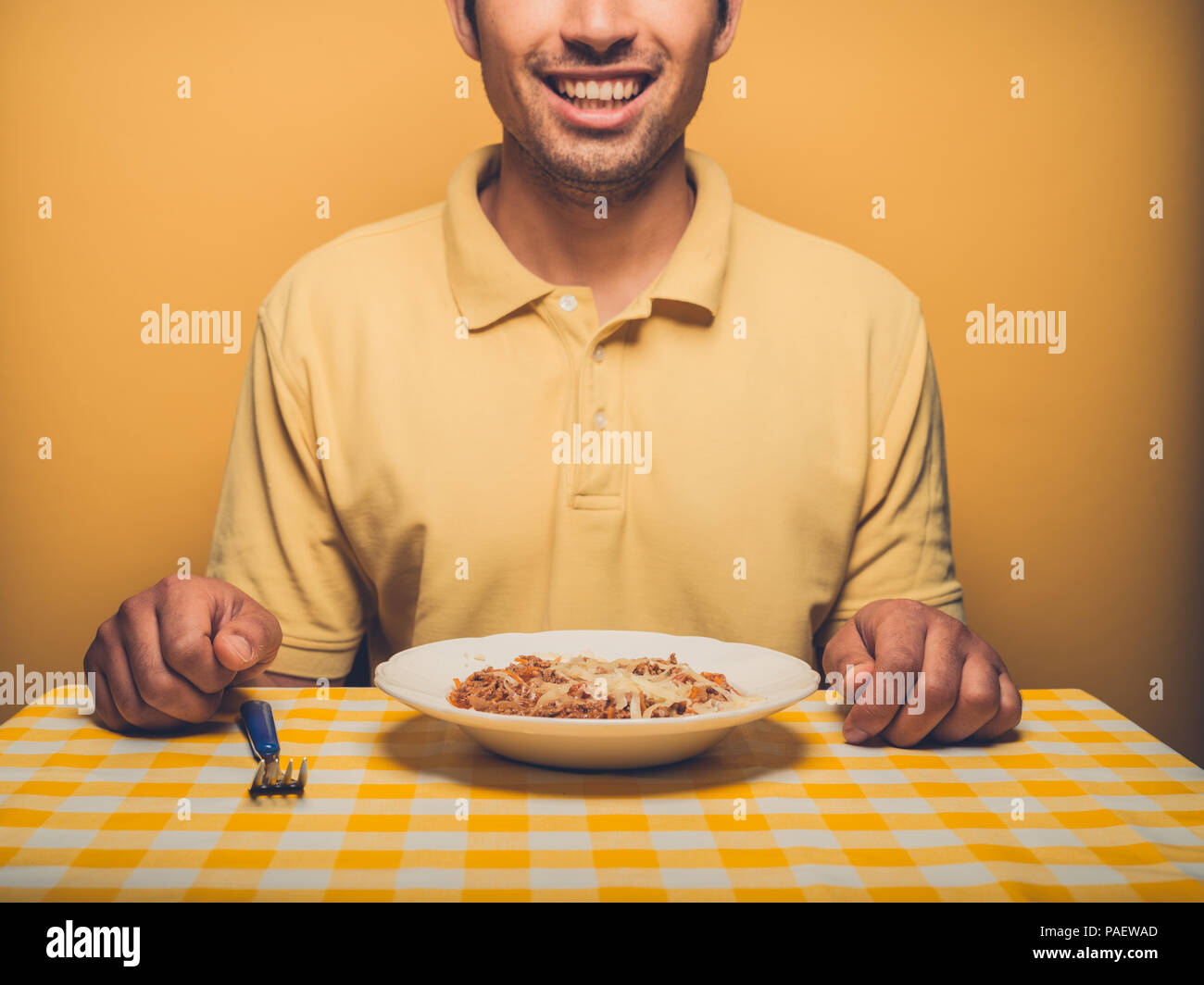 A young man against a yellow backdrop is eating mince Stock Photo - Alamy