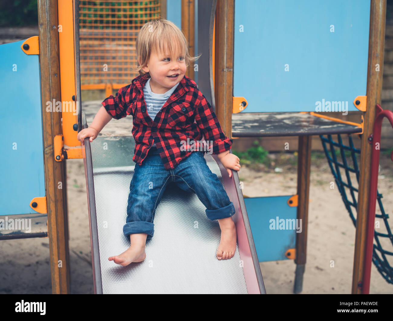 A little toddler is coming down the slide at the playground Stock Photo ...