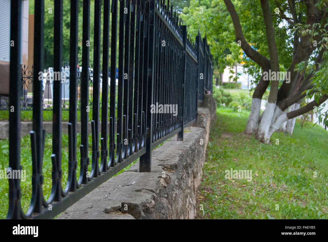 Black forged fence on a concrete foundation. Side view, perspective ...